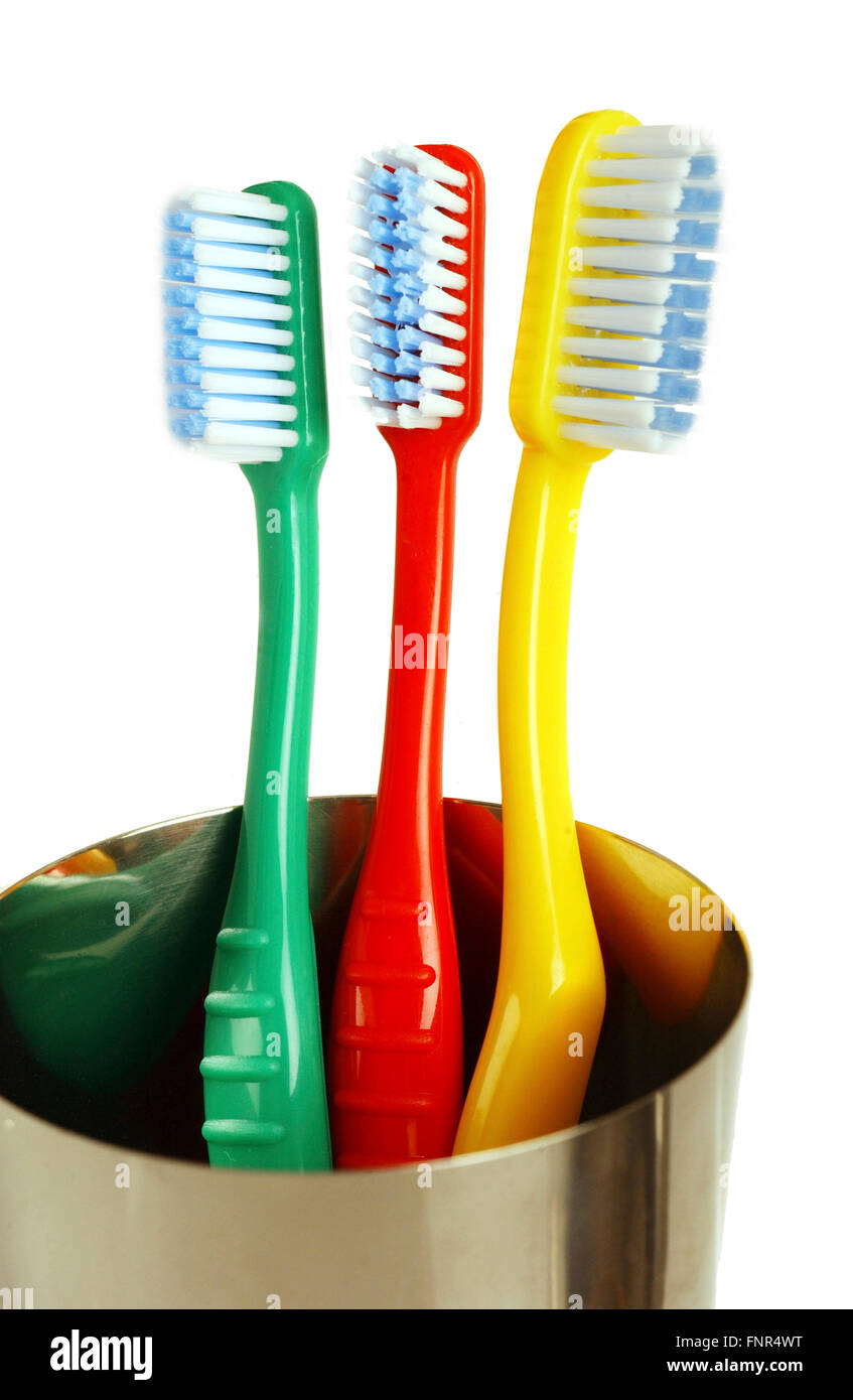 Three different colored toothbrushes in a silver cup Stock Photo - Alamy