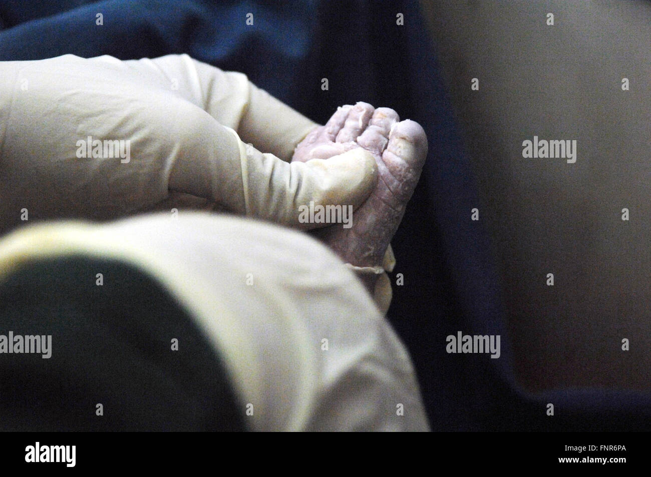 A gloved hand holds onto a the left foot of a new born baby Stock Photo ...