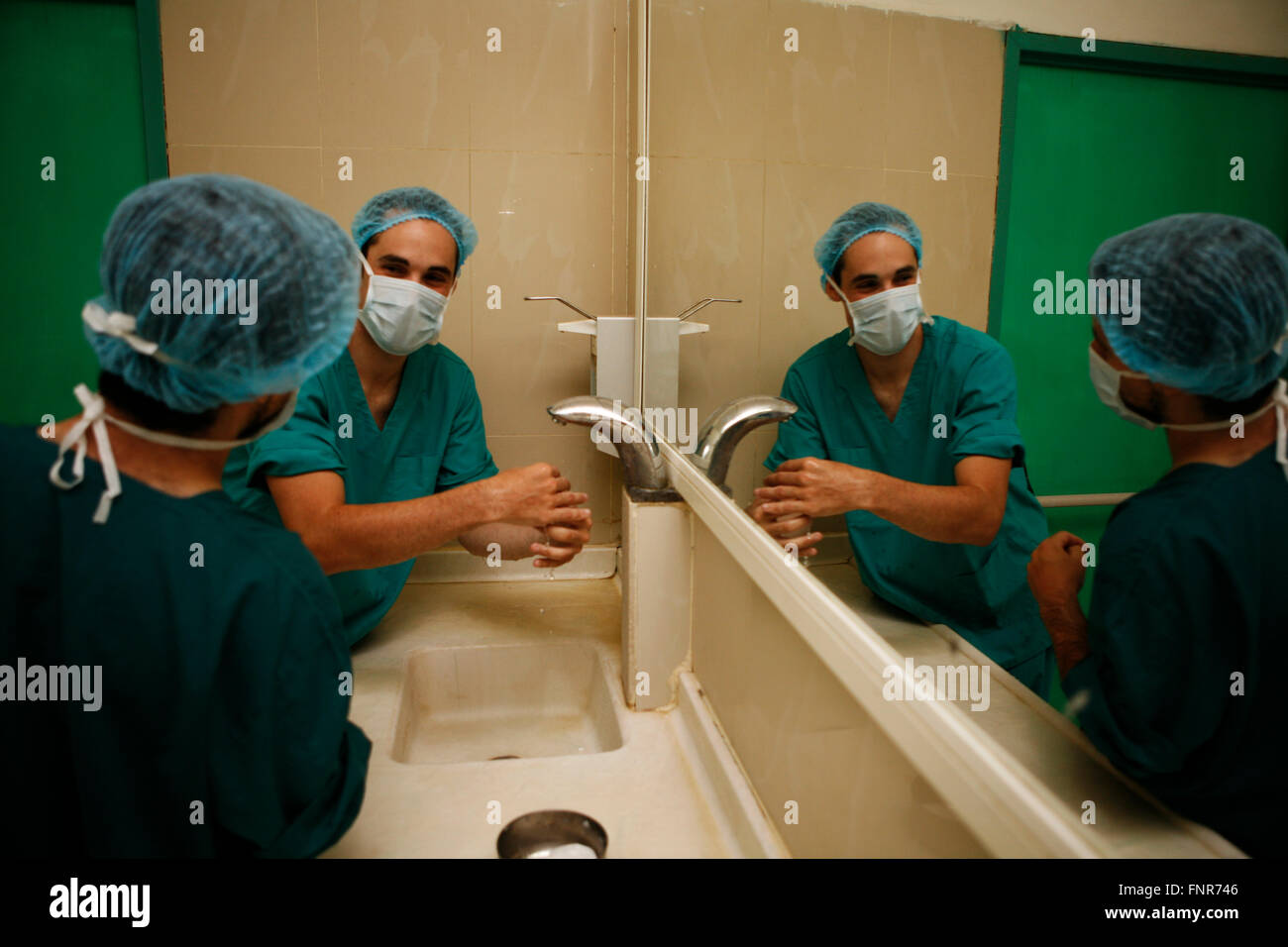 Two surgeons thoroughly washing their hands and arms prior to ...