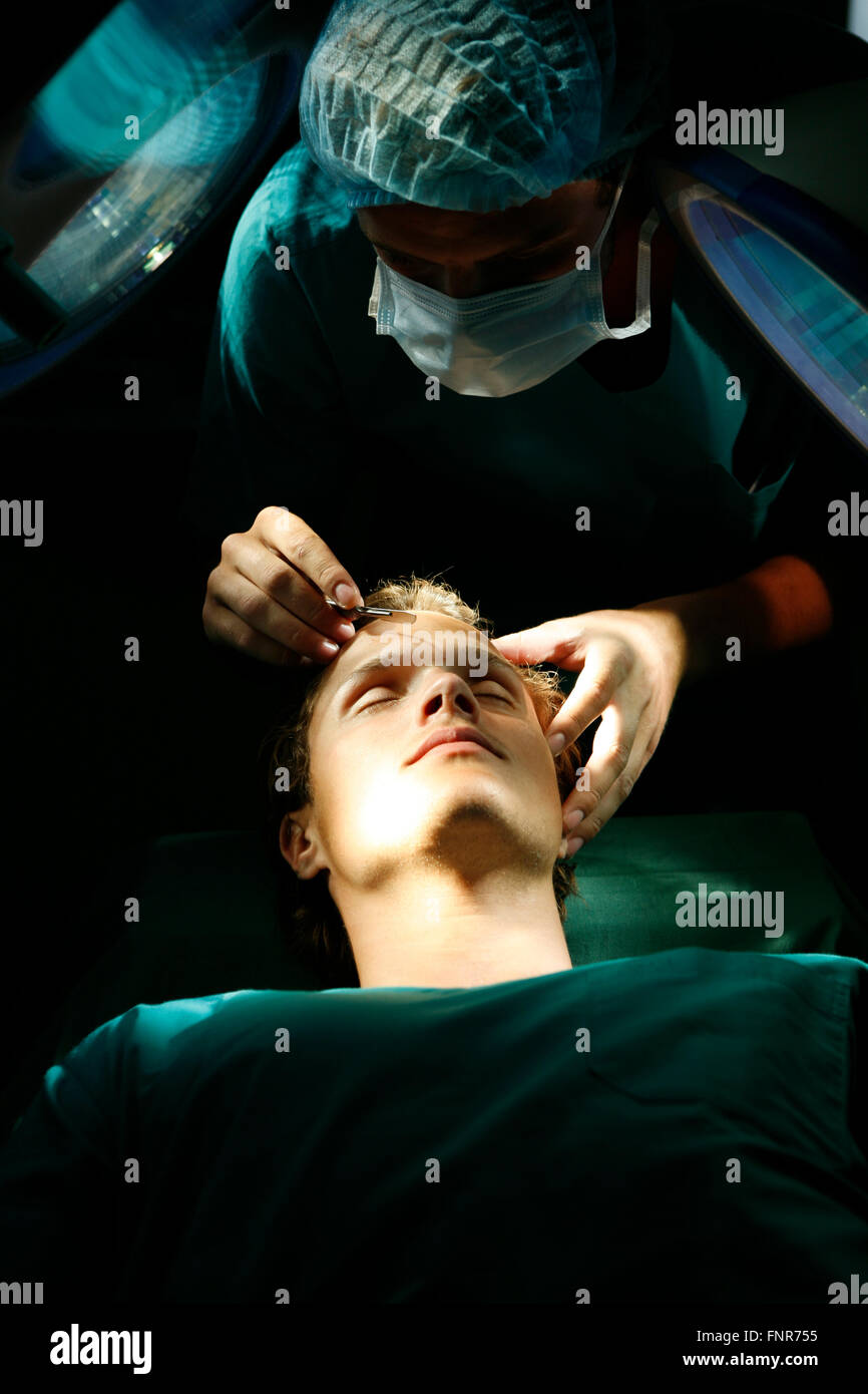 A surgeon prepares to make a surgical incision into the forehead of a ...