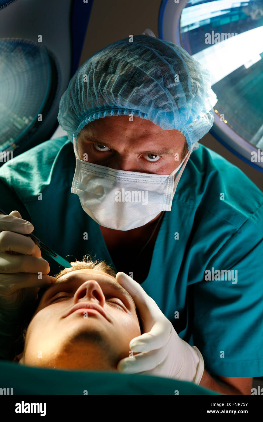 A surgeon prepares to makes a surgical incision into the forehead of a ...