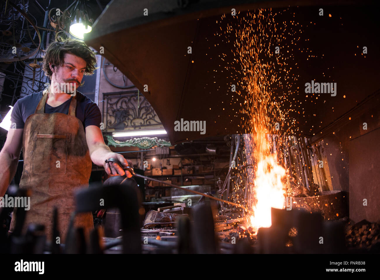 Ironworker forging hot iron in workshop Stock Photo - Alamy
