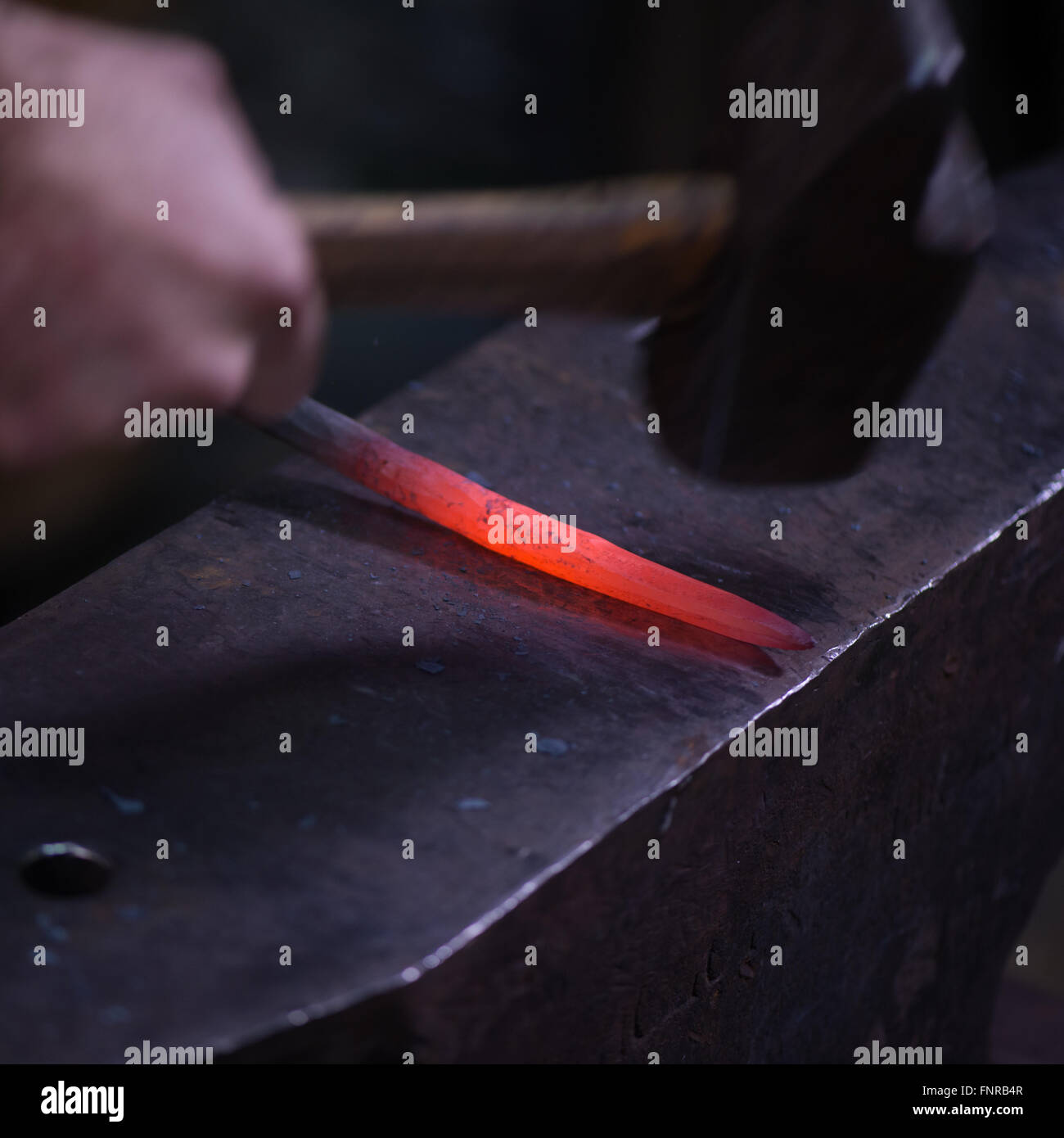 Ironworker forging hot iron in workshop Stock Photo - Alamy