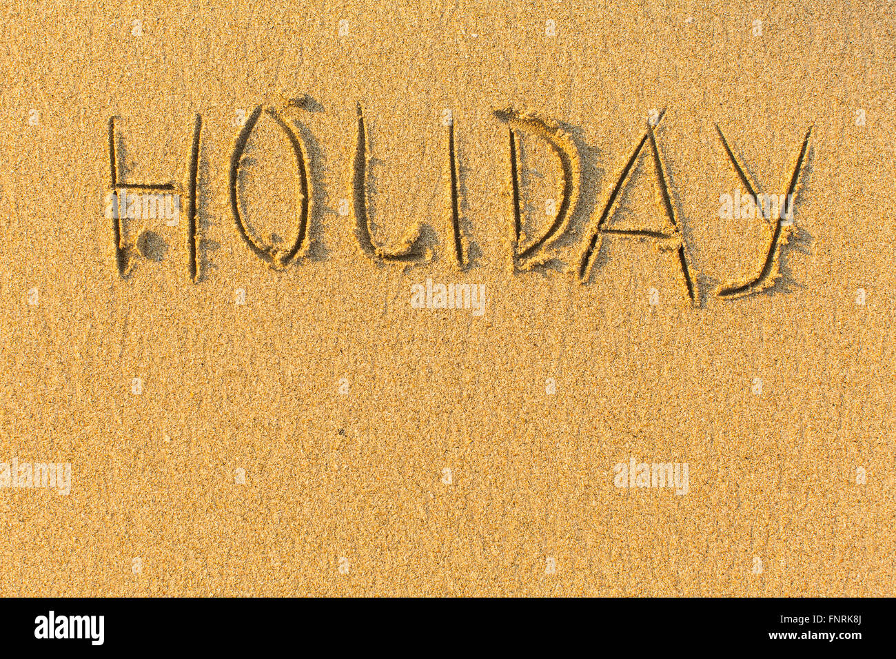 Holiday - word drawn on the sand beach Stock Photo - Alamy