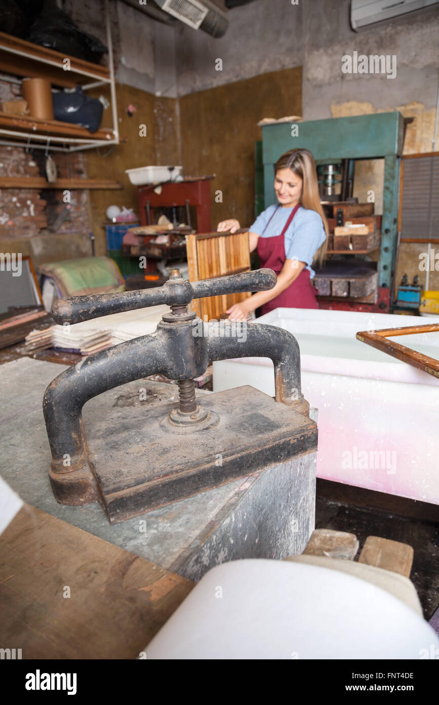 Closeup of paper press machine with worker working in background at ...