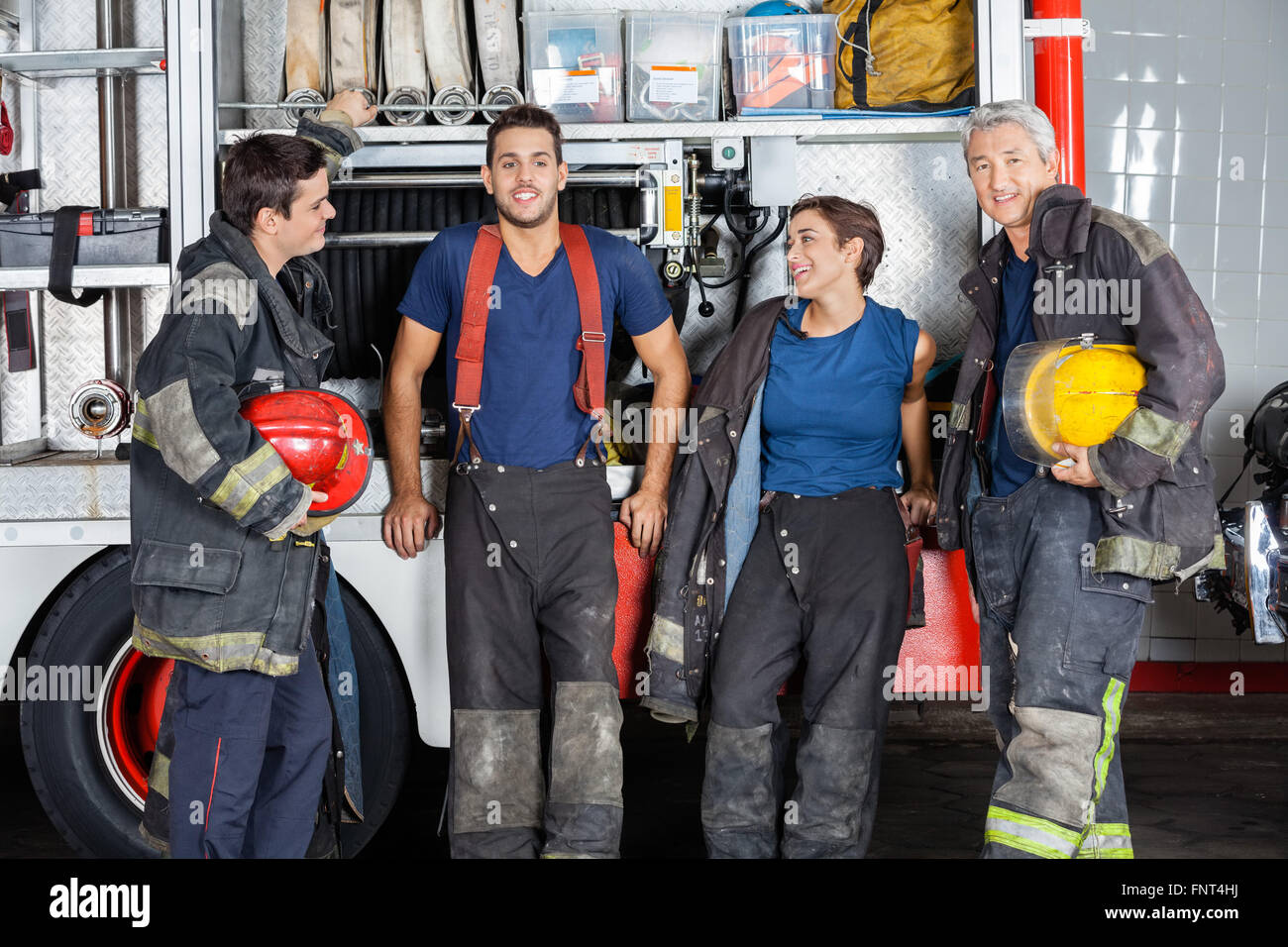 Team of confident firefighters leaning on truck at fire station Stock ...