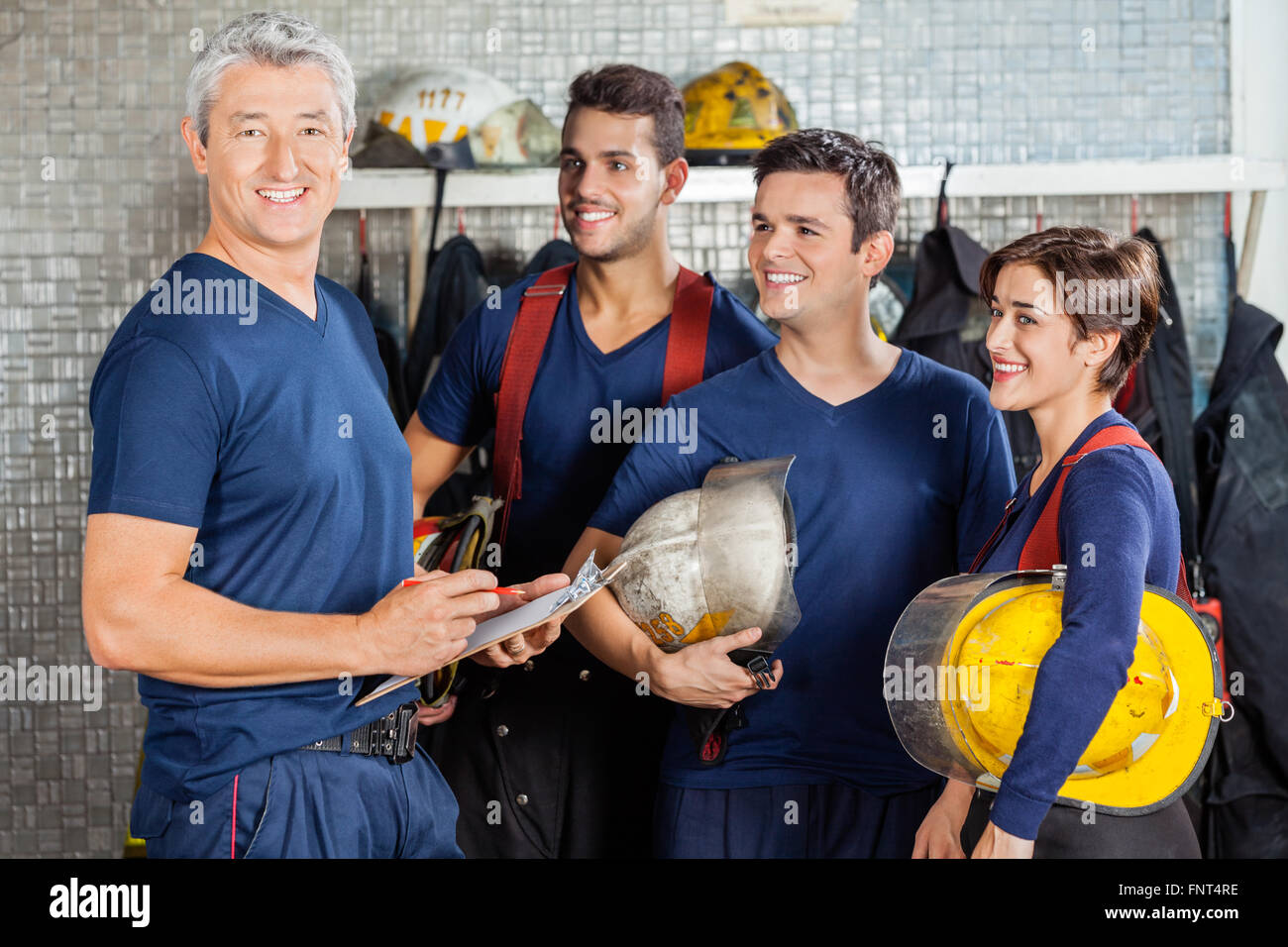 Portrait of happy fireman standing with team at fire station Stock ...