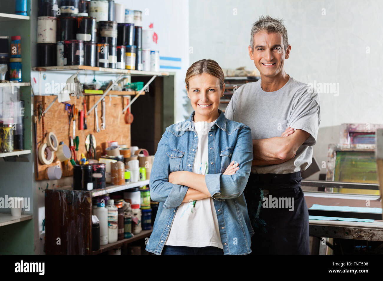 Portrait of smiling male and female workers standing arms crossed at ...