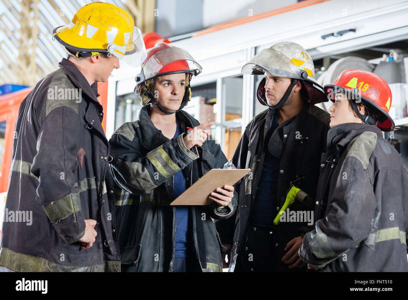 Male firefighter gesturing while discussing with colleagues at fire ...
