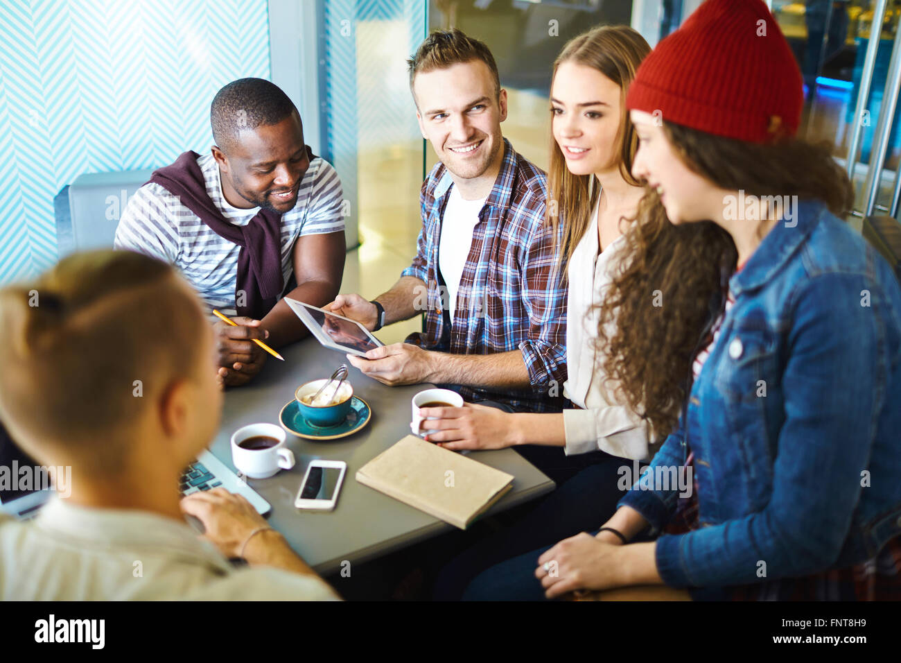 Group of young people sitting at cafe and communicating Stock Photo - Alamy
