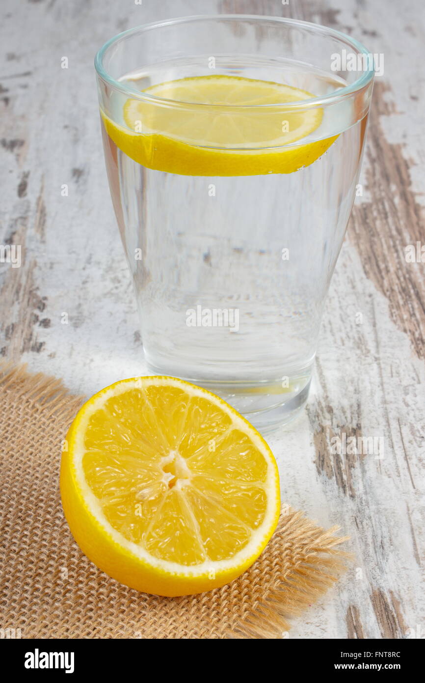 Fresh lemon and full glass of clean water with slice of lemon on old ...