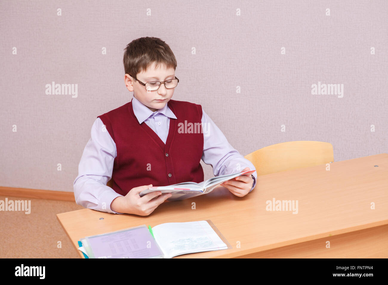 boy reads a book while sitting at a desk Stock Photo - Alamy
