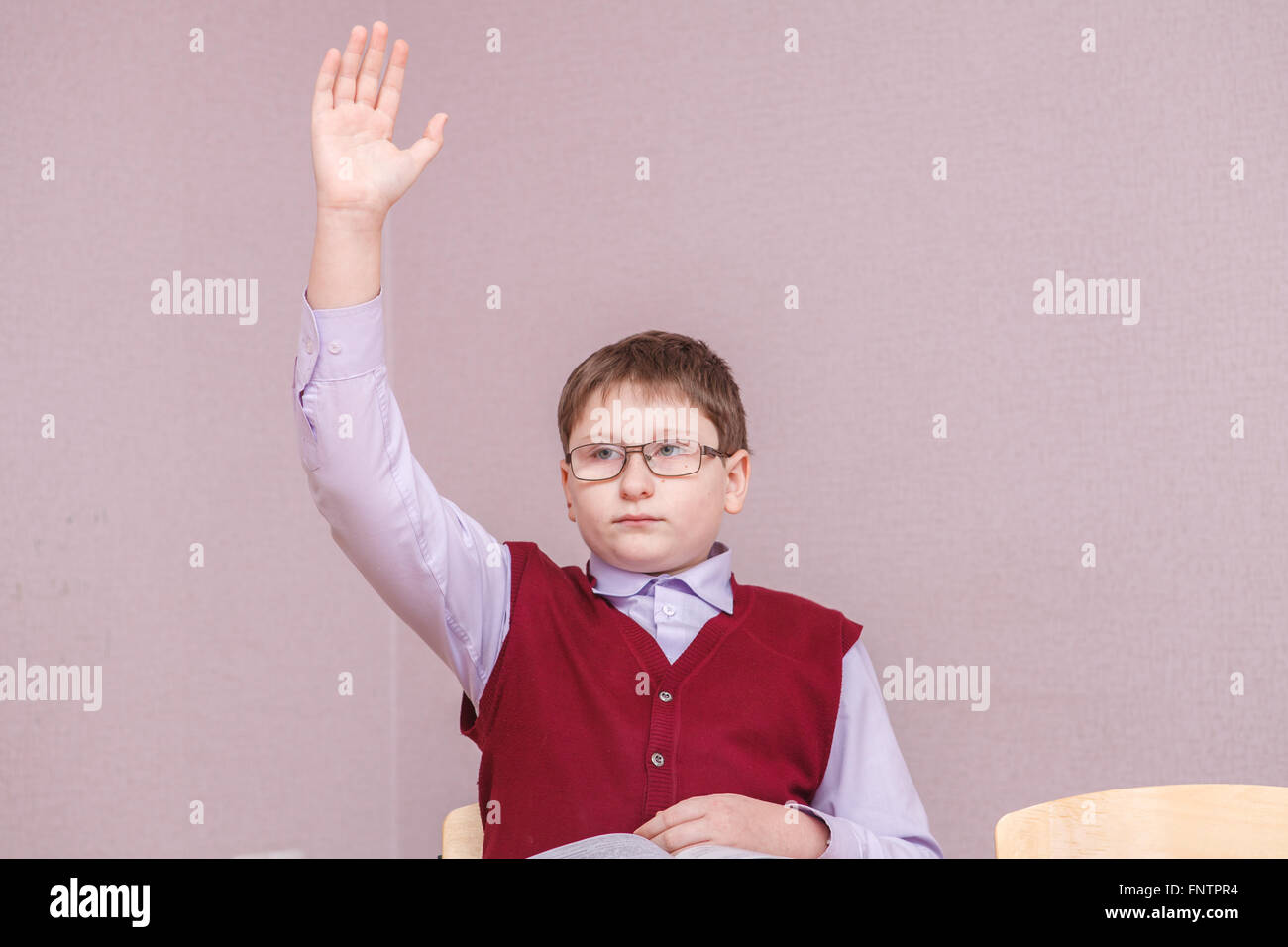 boy pulls a hand up sitting at his desk Stock Photo - Alamy