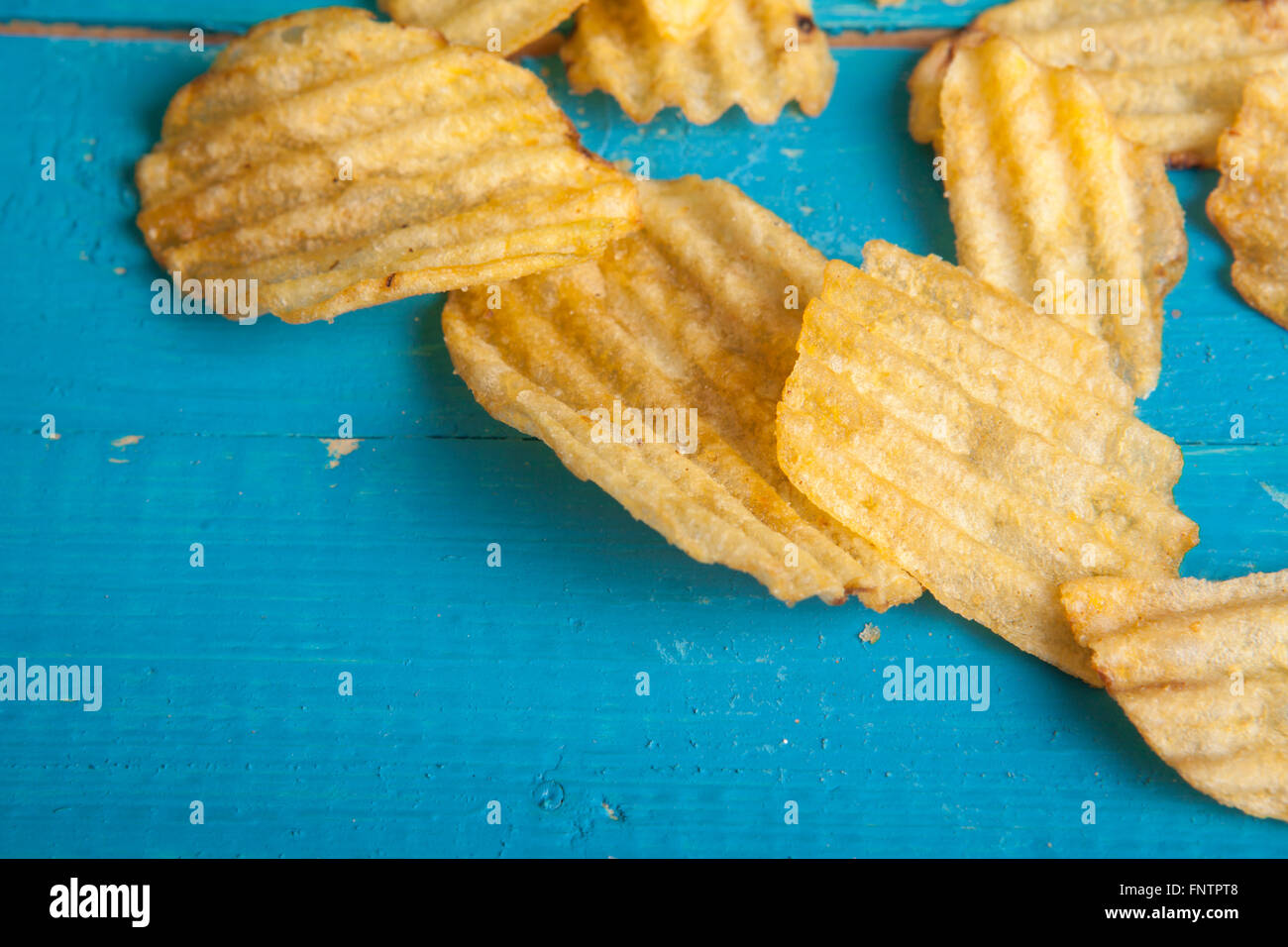 potato chips scattered on a blue wooden table Stock Photo - Alamy