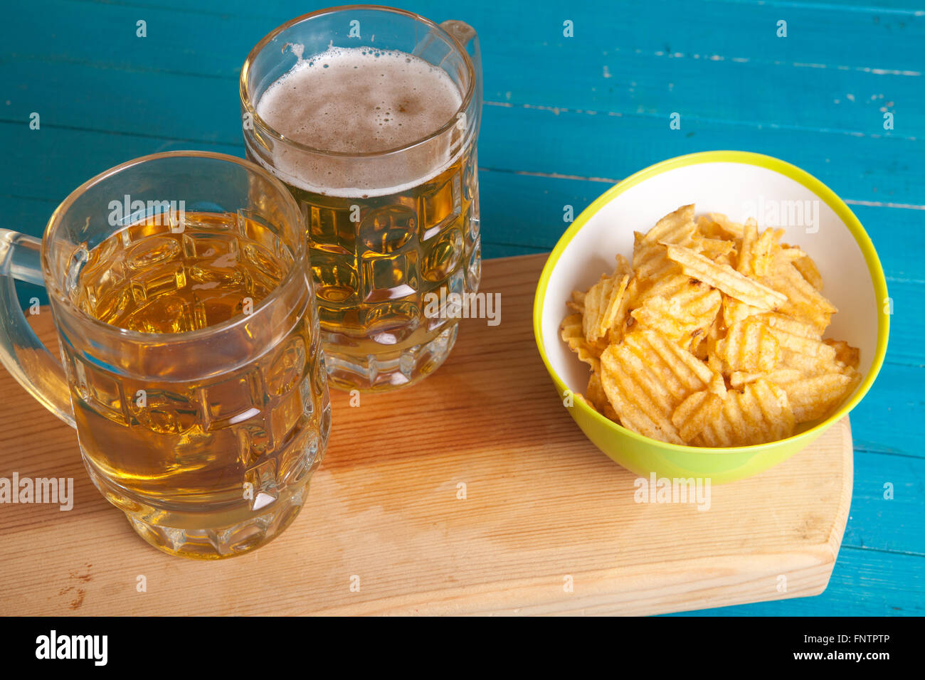 potato chips and two mugs of beer on the table Stock Photo - Alamy
