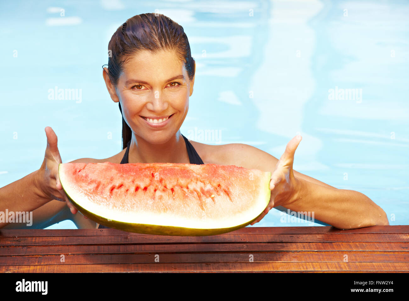 Attractive smiling woman holding watermelon in swimming pool Stock ...