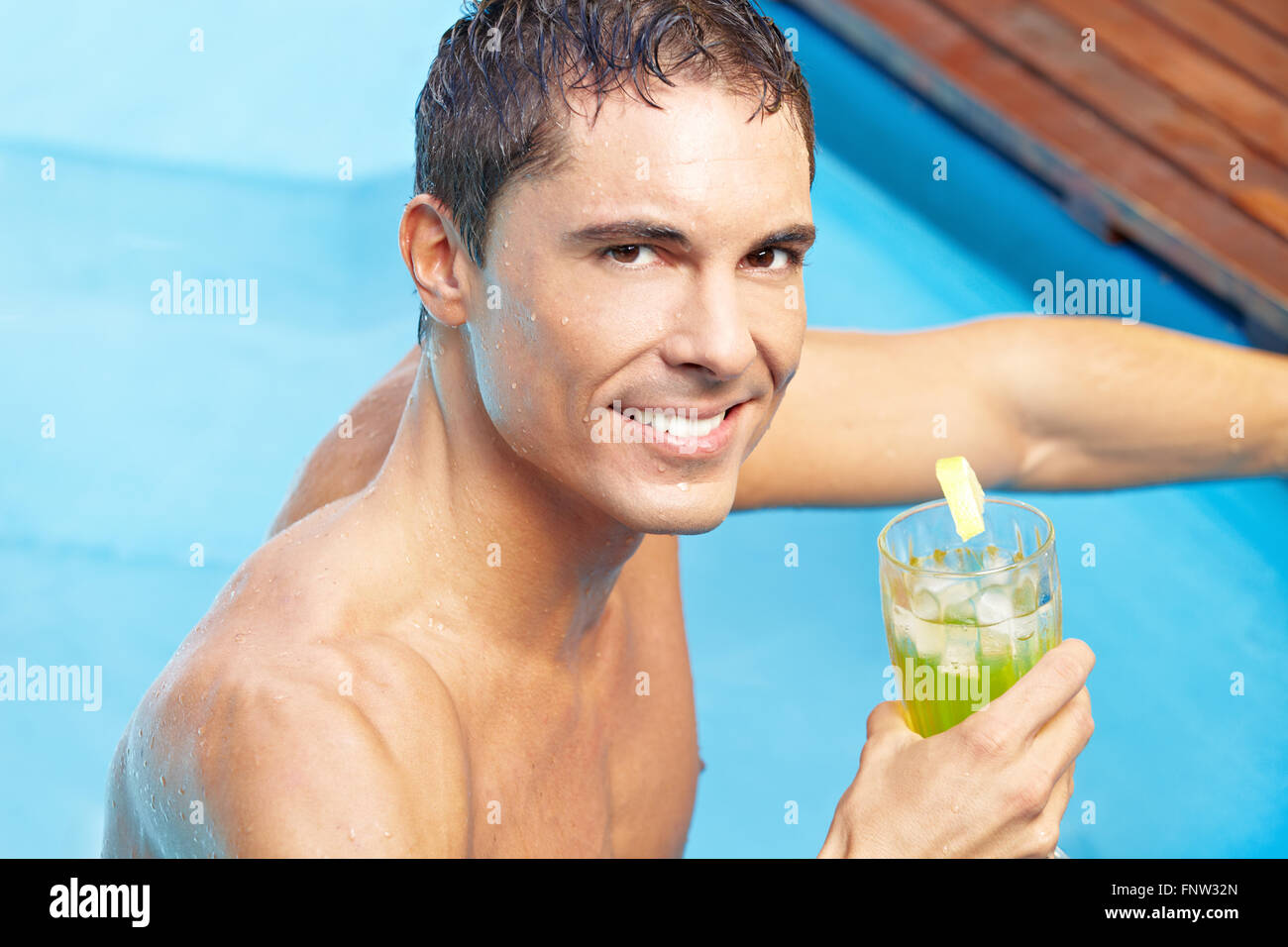 Smiling attractive man with cocktail drink in swimming pool Stock Photo ...