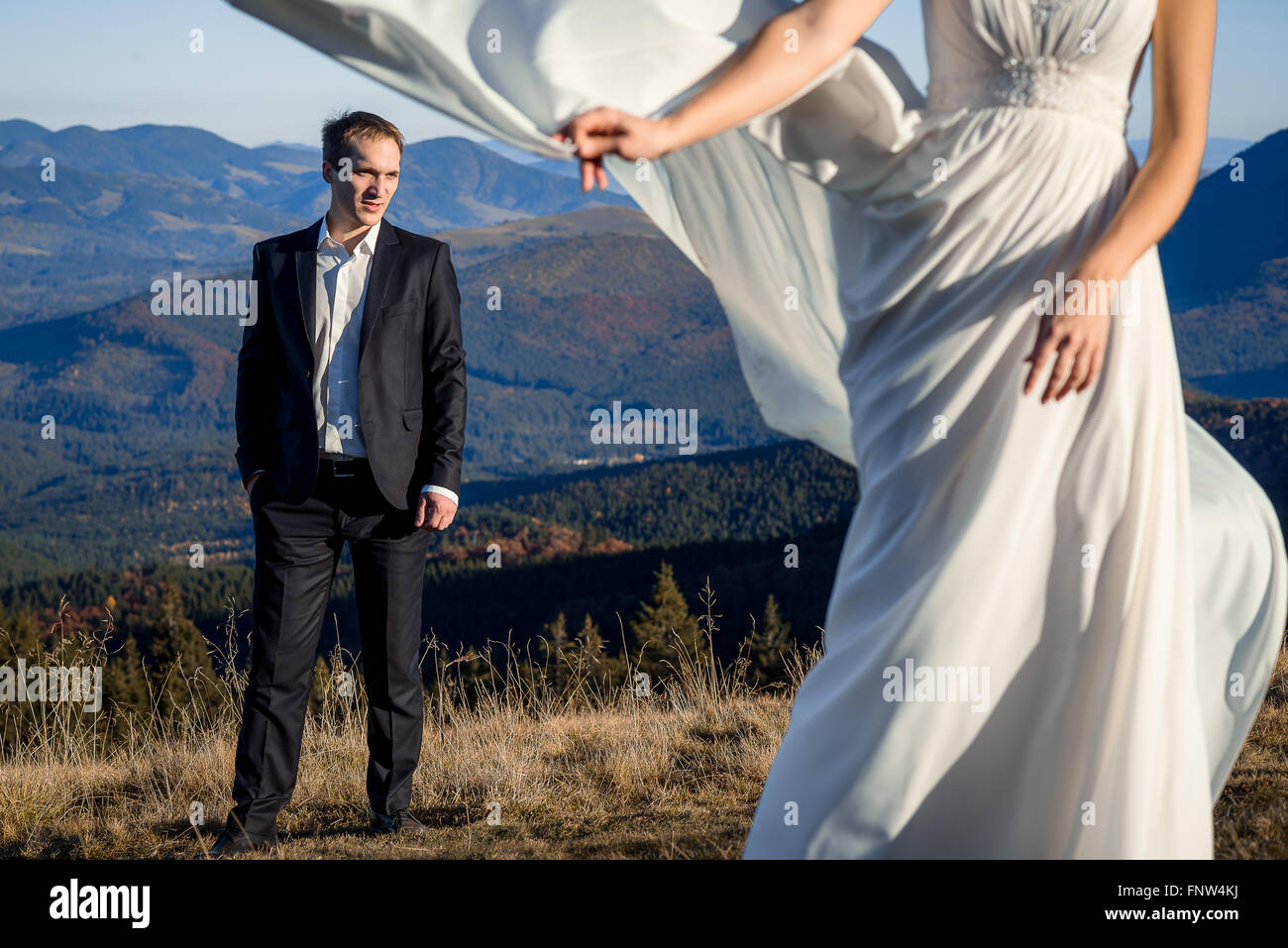 Handsome groom looking at his beatiful bride posing on foreground ...