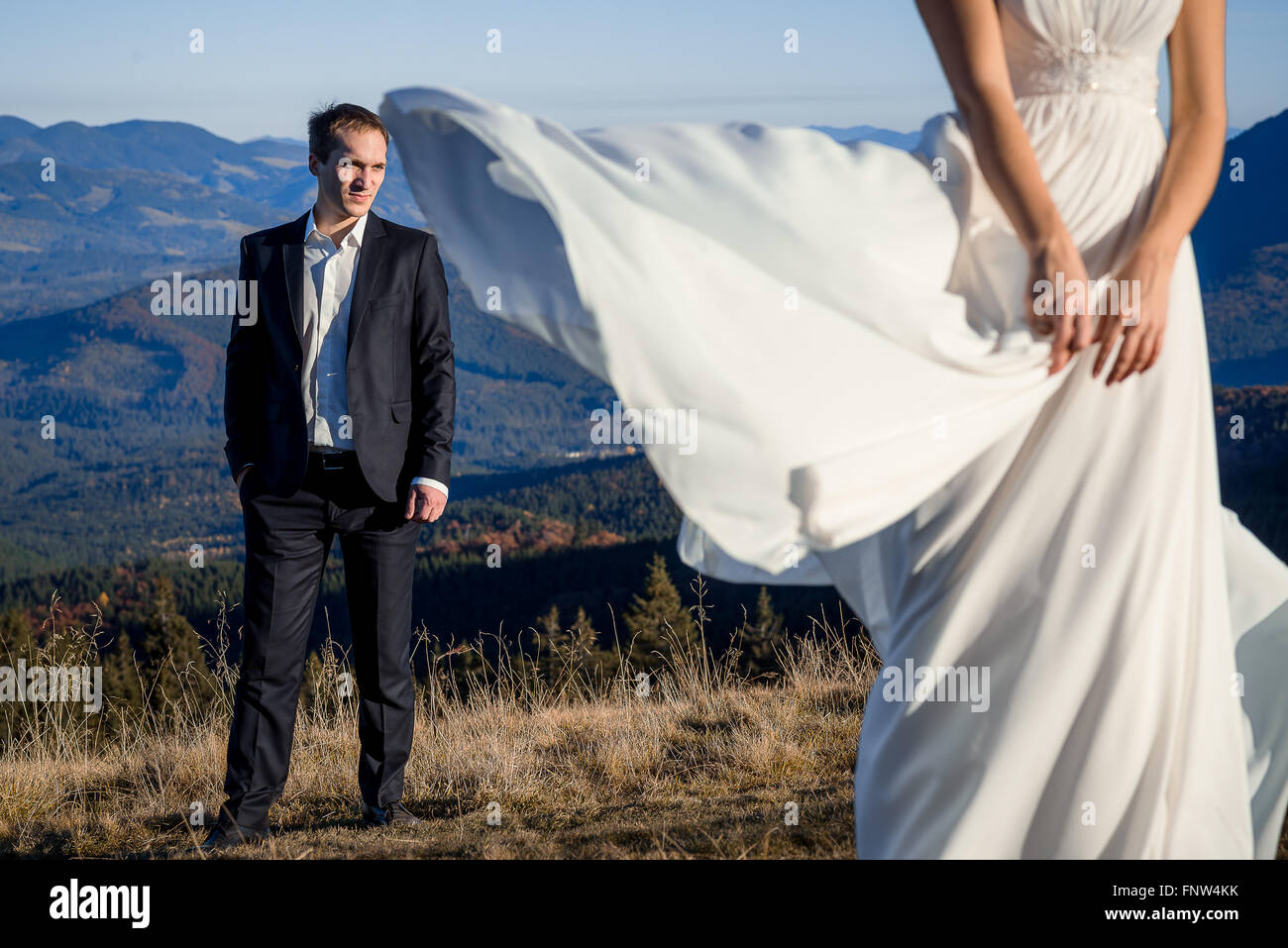 Handsome groom looking at his beatiful bride posing on foreground ...