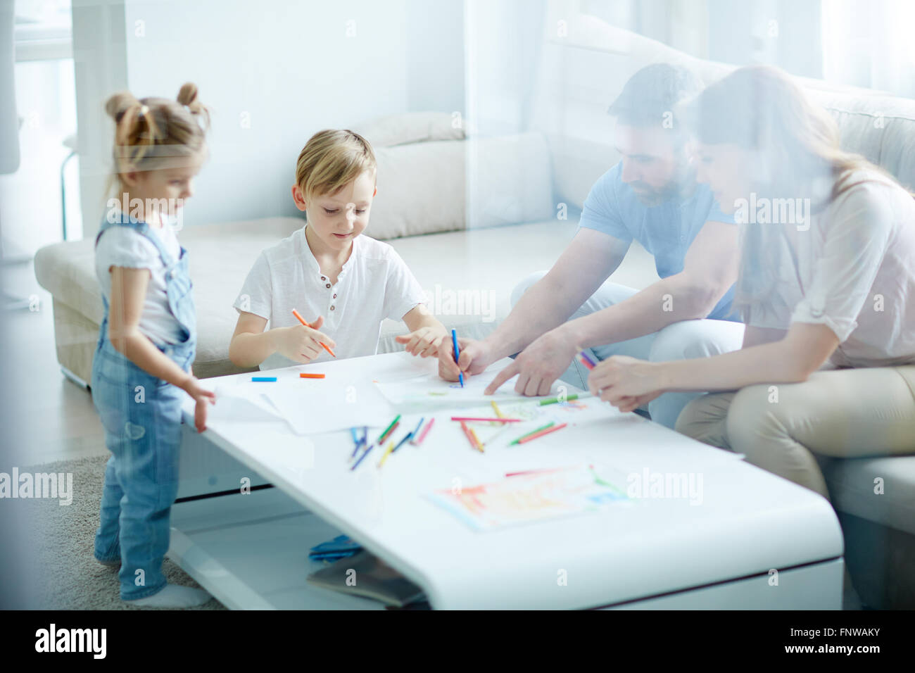 Children drawing at the table with their parents Stock Photo - Alamy