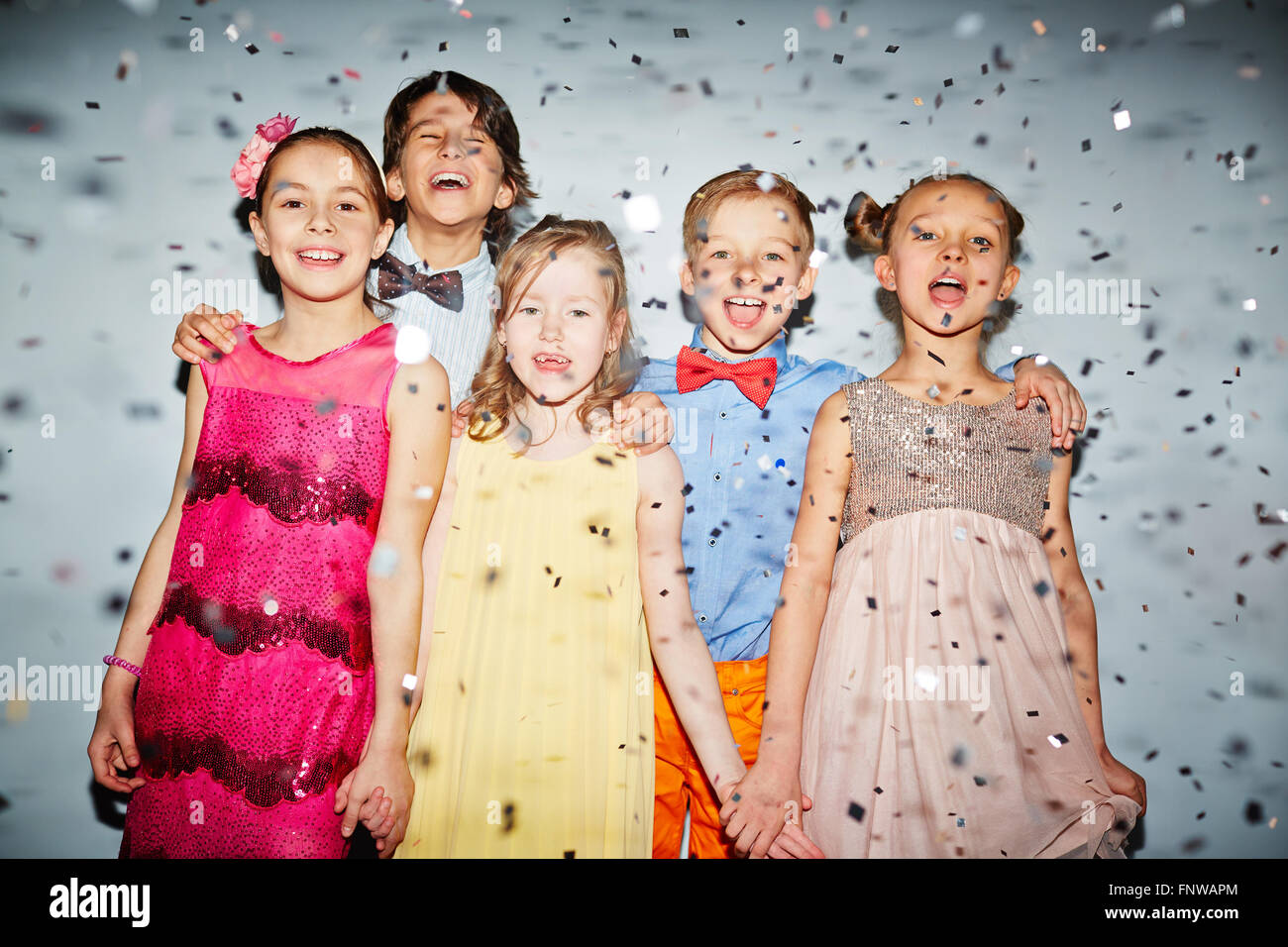 Group of happy children standing under falling confetti Stock Photo - Alamy