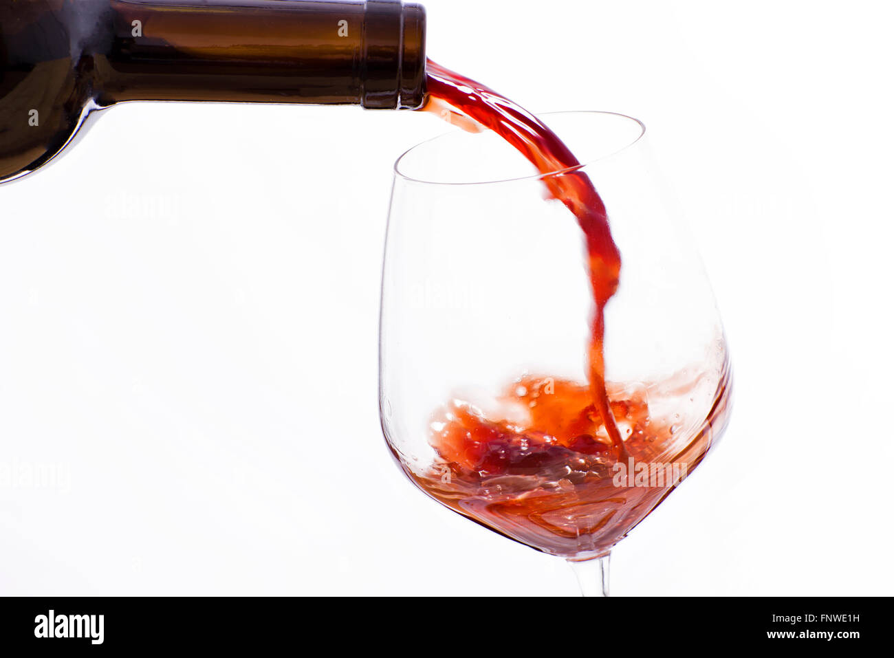 Wine poured from a bottle in a wine glass, on a white background Stock ...