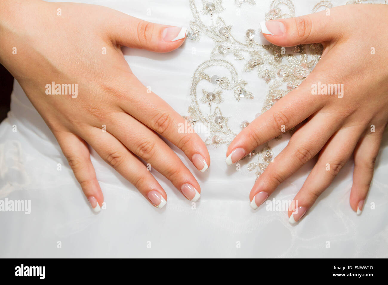 Hands of the bride on a white wedding dress Stock Photo - Alamy