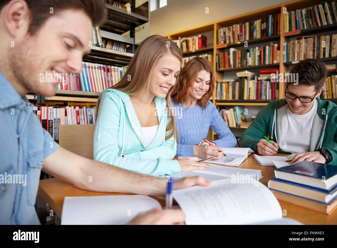 happy students writing to notebooks in library Stock Photo - Alamy