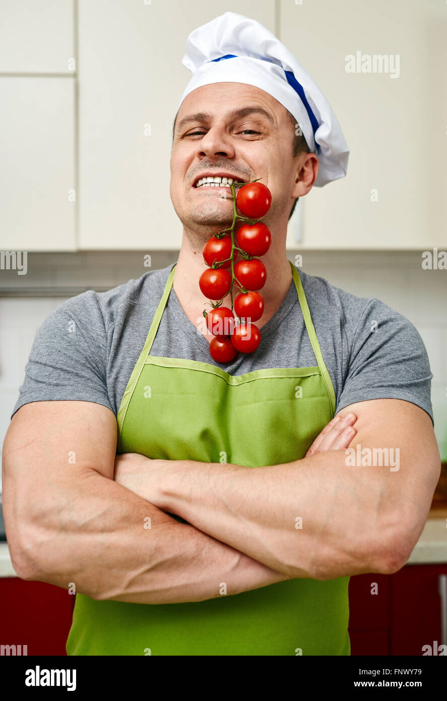 Fit muscular chef holding a bunch of cherry tomatoes in his teeth Stock ...