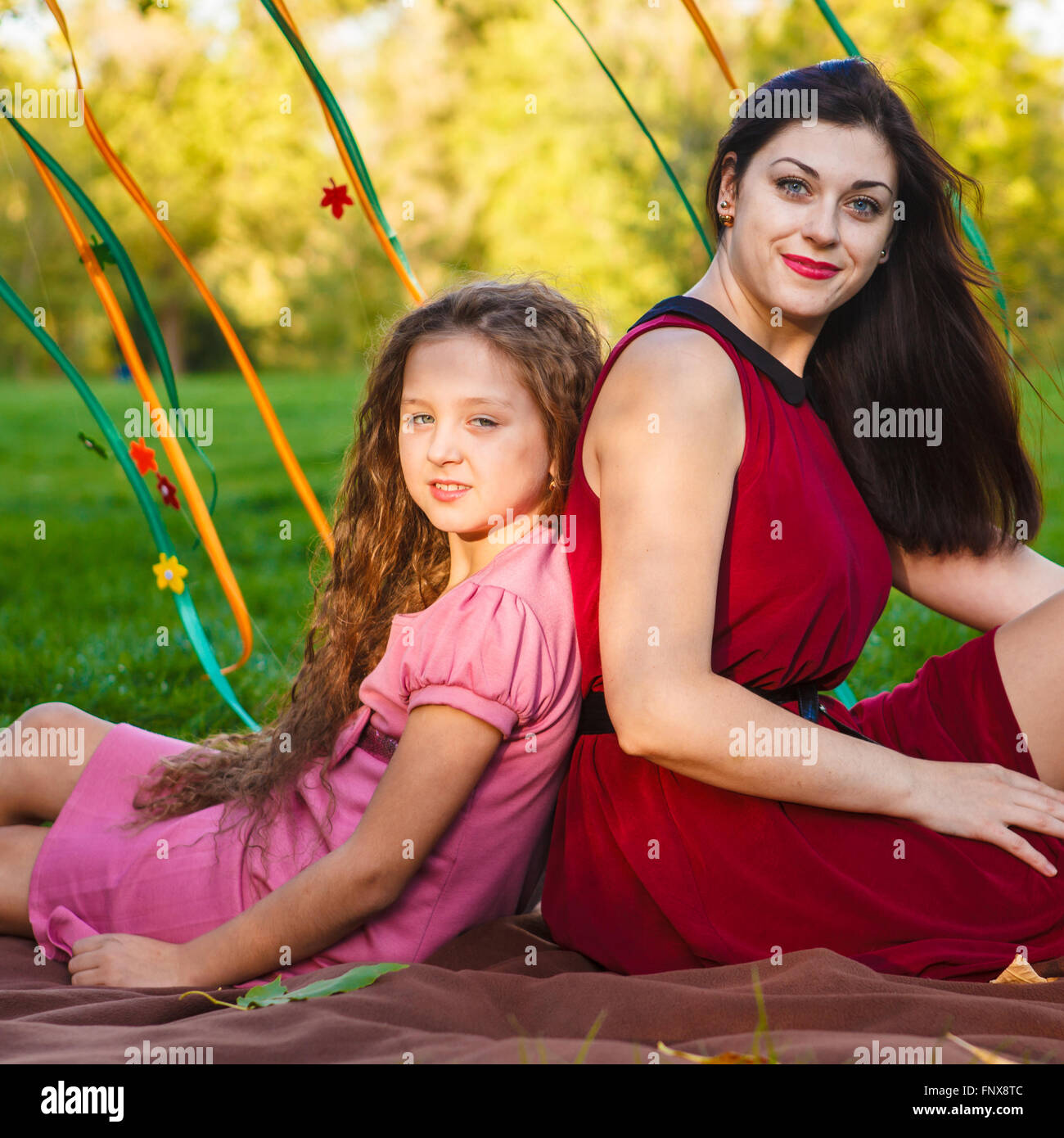 Mom and daughter in the park sitting back to back on a plaid Stock ...