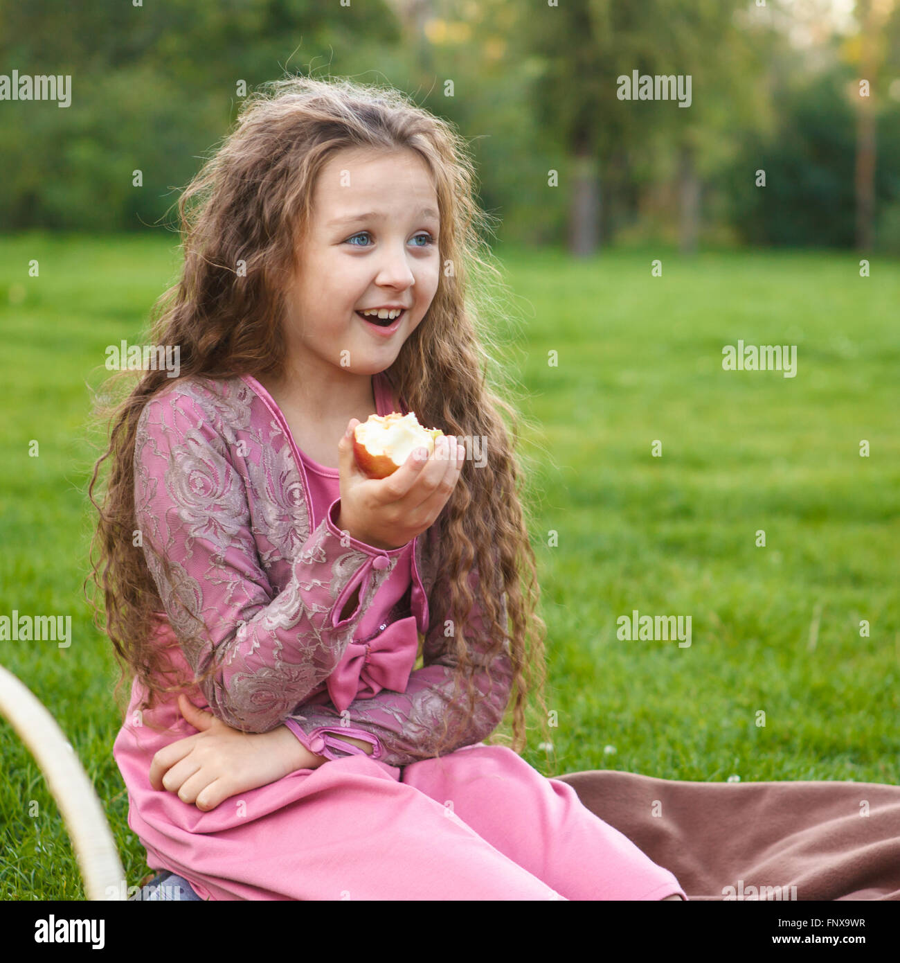 girl eating an apple in a summer park sitting on a plaid Stock Photo ...