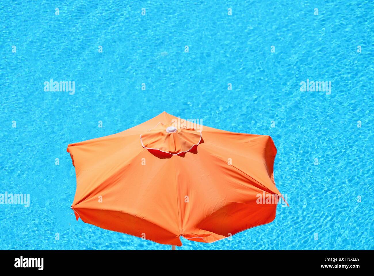 holiday swimming pool background with orange contrast umbrella parasol ...