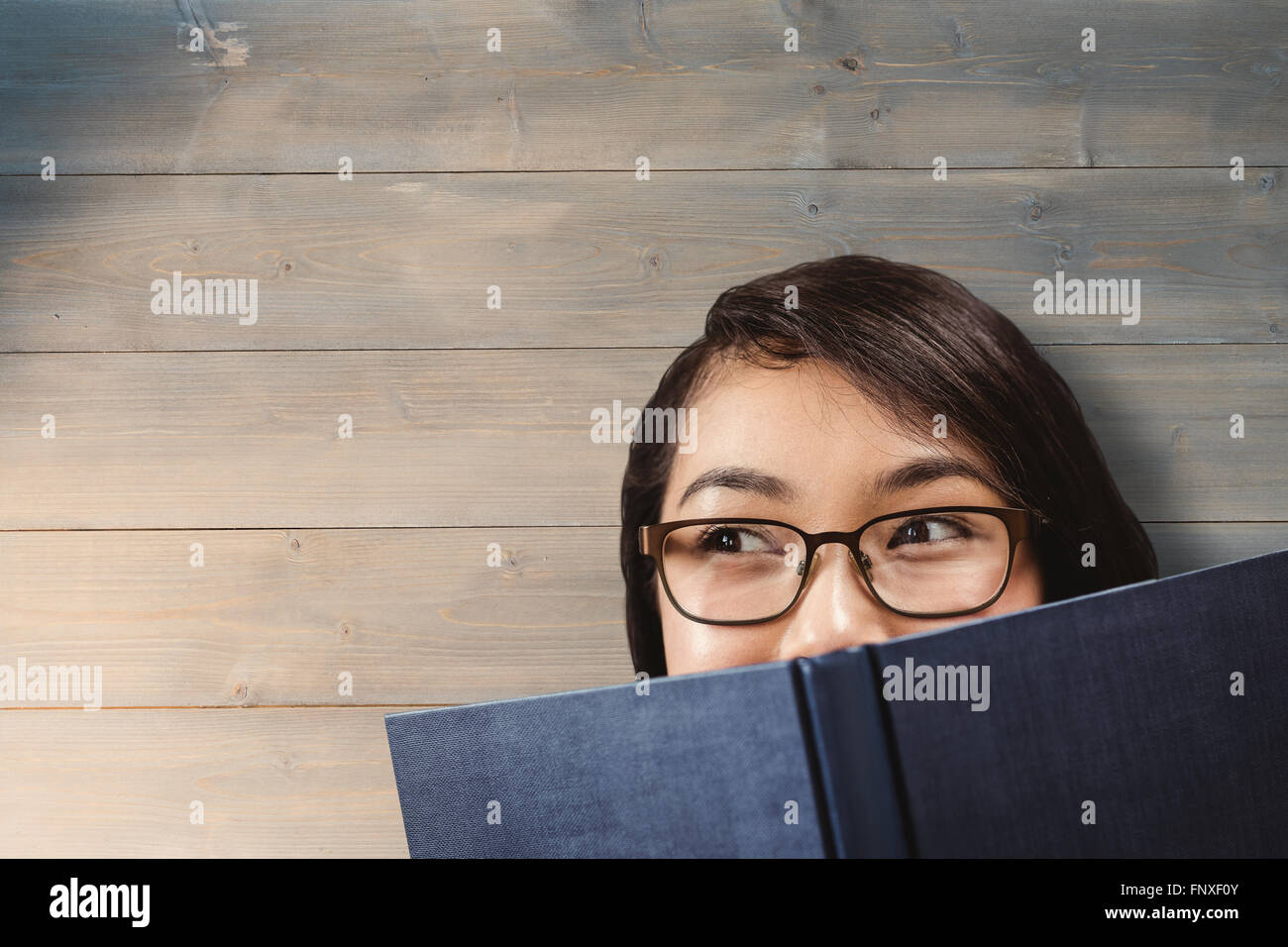Composite image of pretty student hiding face behind a book Stock Photo ...