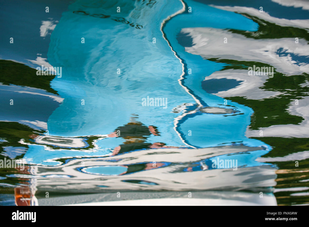 reflection of a sailing dinghy in a watery ripple on a calm stretch of ...