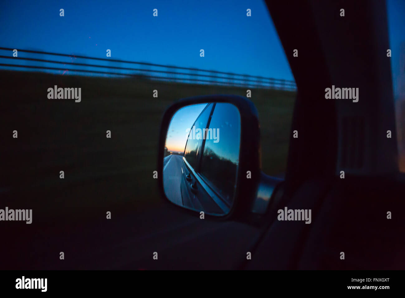 Sunrise reflected in the mirror of a car or van traveling at speed down ...