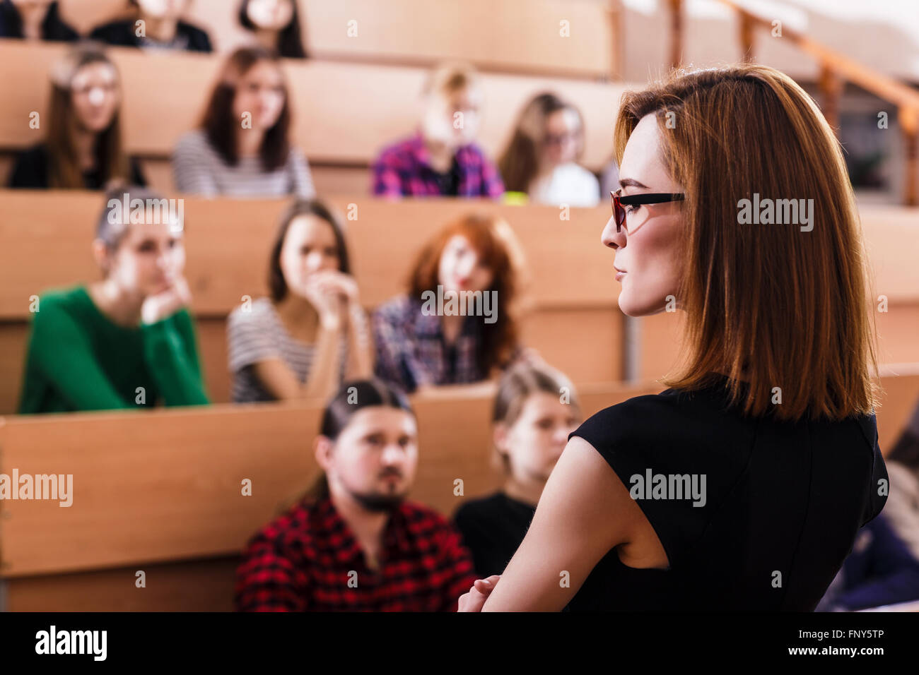 Young female teacher explaining something to students in classroom ...