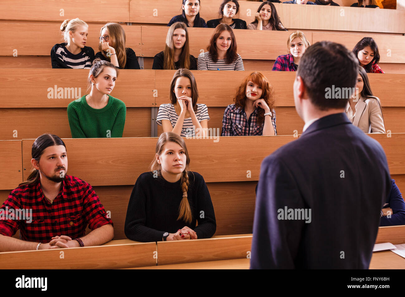 Teacher explaining something to students in classroom Stock Photo - Alamy