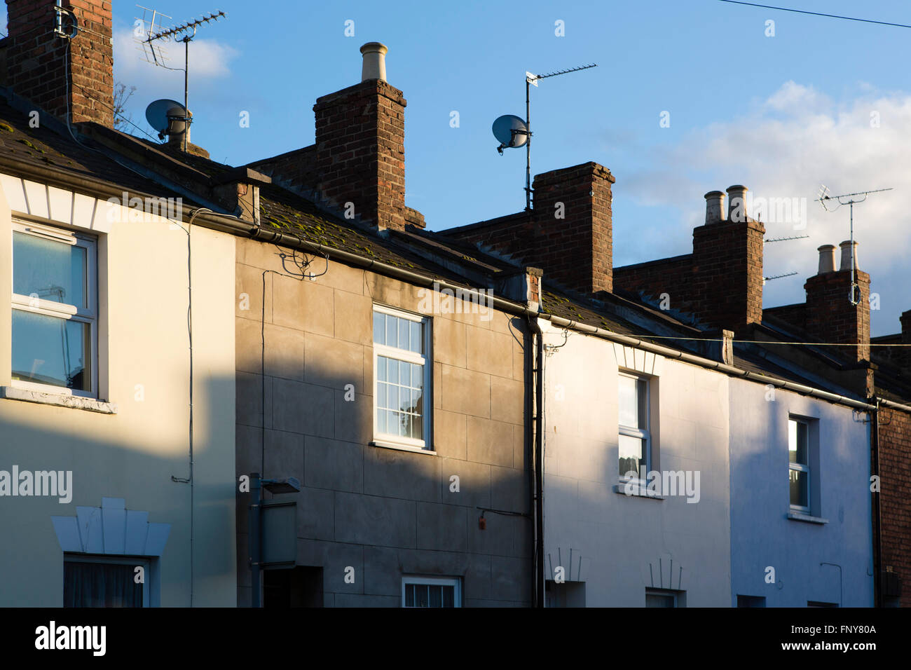 A row of terraced housing and rooftops in a town in the UK with shadows ...
