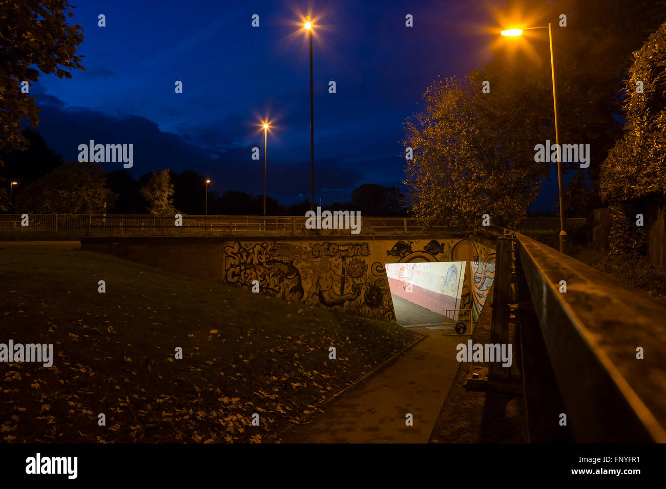 Night time street scene with illuminated underpass and graffiti on a ...