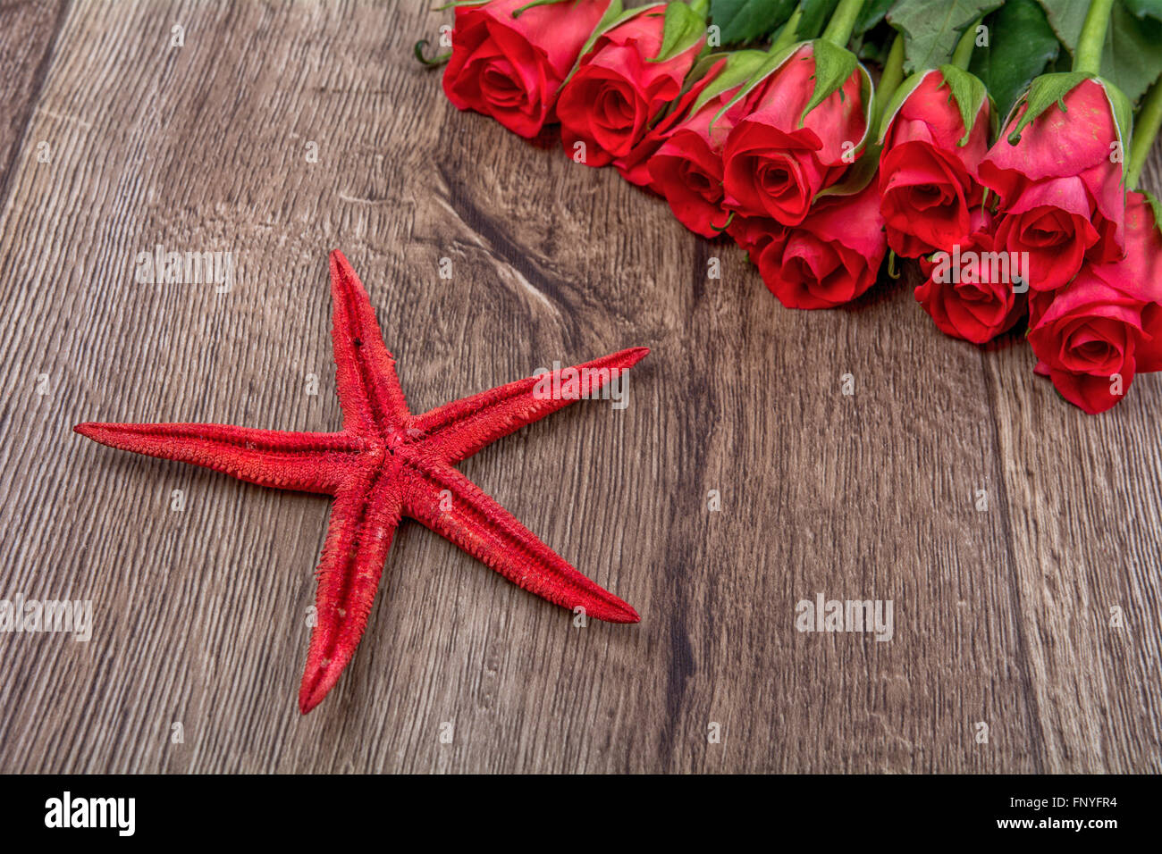 Red starfish and red roses on a wooden background Stock Photo - Alamy