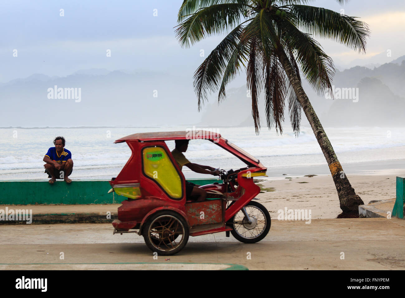 Close up of red native bike taxi driving on beach road on a misty day ...