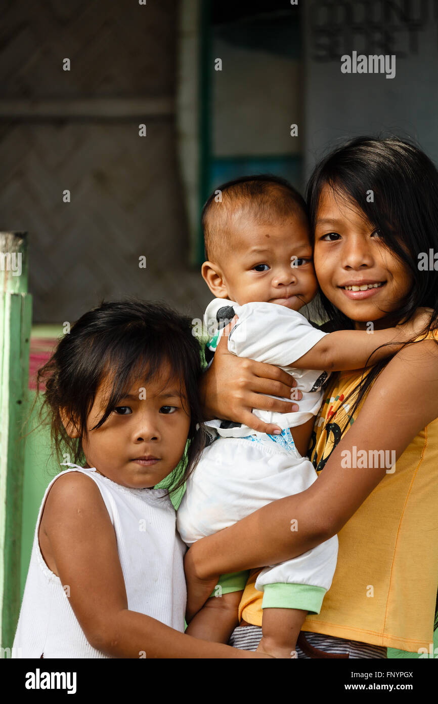 3 children - two girls and a baby, pose in front of store in native ...