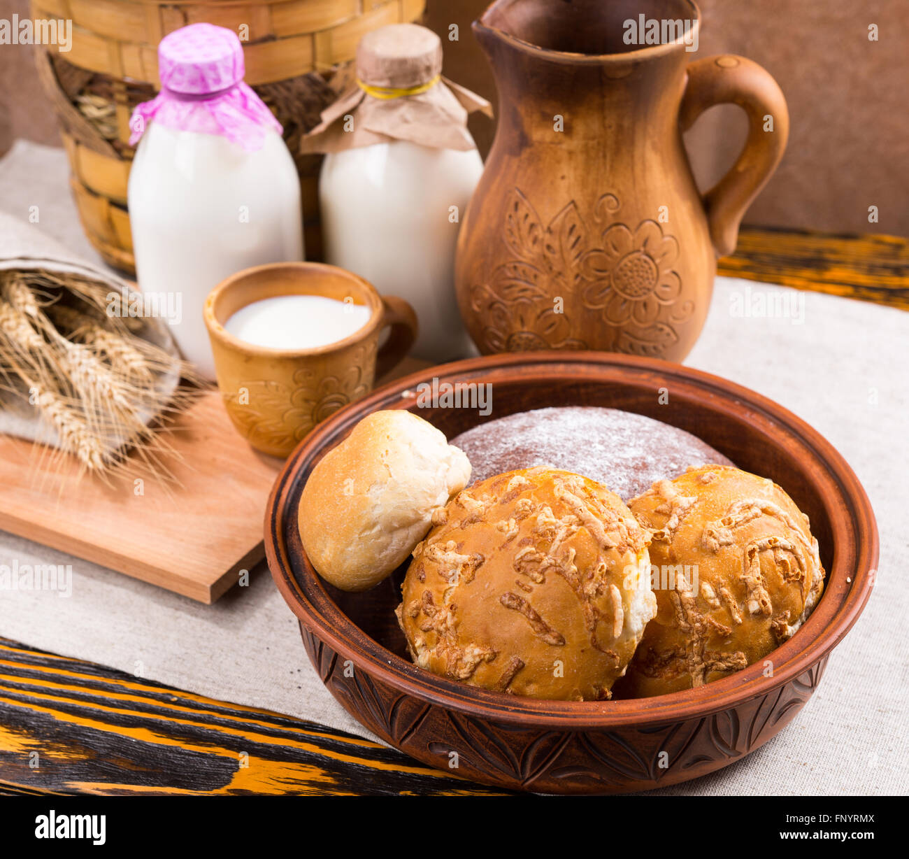 Gourmet freshly baked crusty cheese rolls with fresh milk in pottery ...