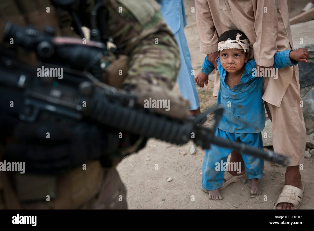 A young Afghan boy watches as U.S. Army soldiers move through a village ...