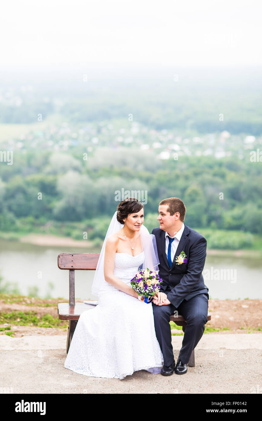 attractive bride and groom sitting on a bench Stock Photo - Alamy