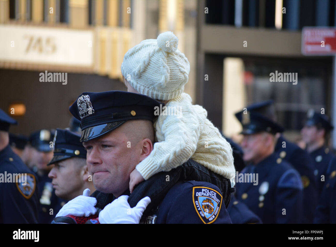 New York, USA. 16th Mar, 2016. NYPD officer carrying a young child ...