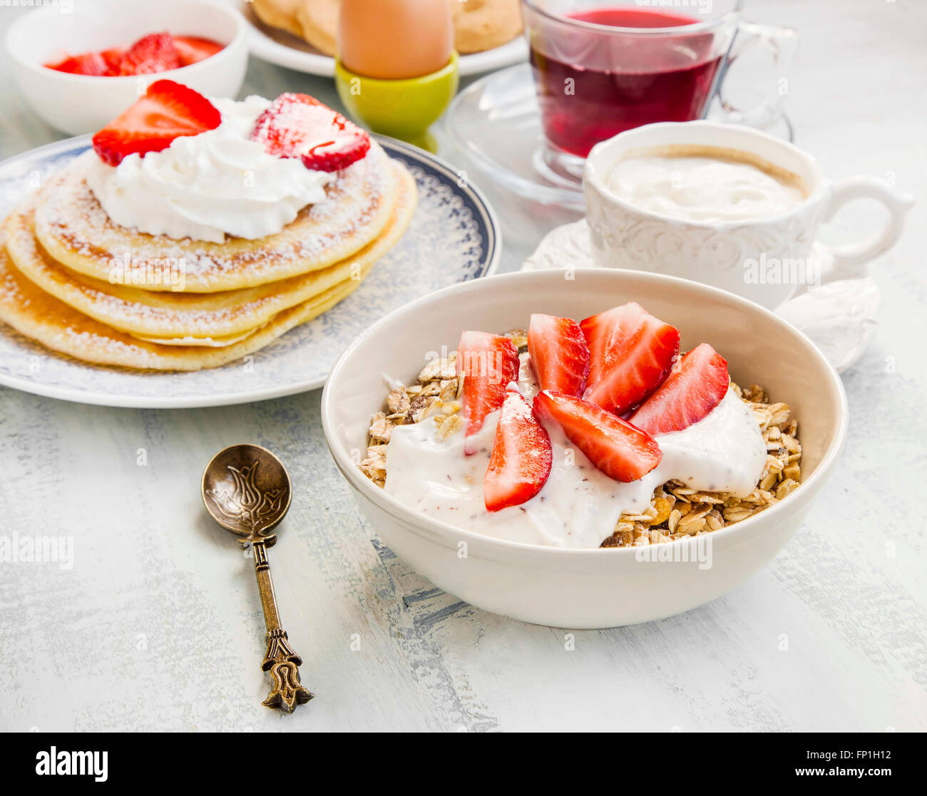 Breakfast meal with musli, yogurt and strawberries, tea, coffee cup and ...