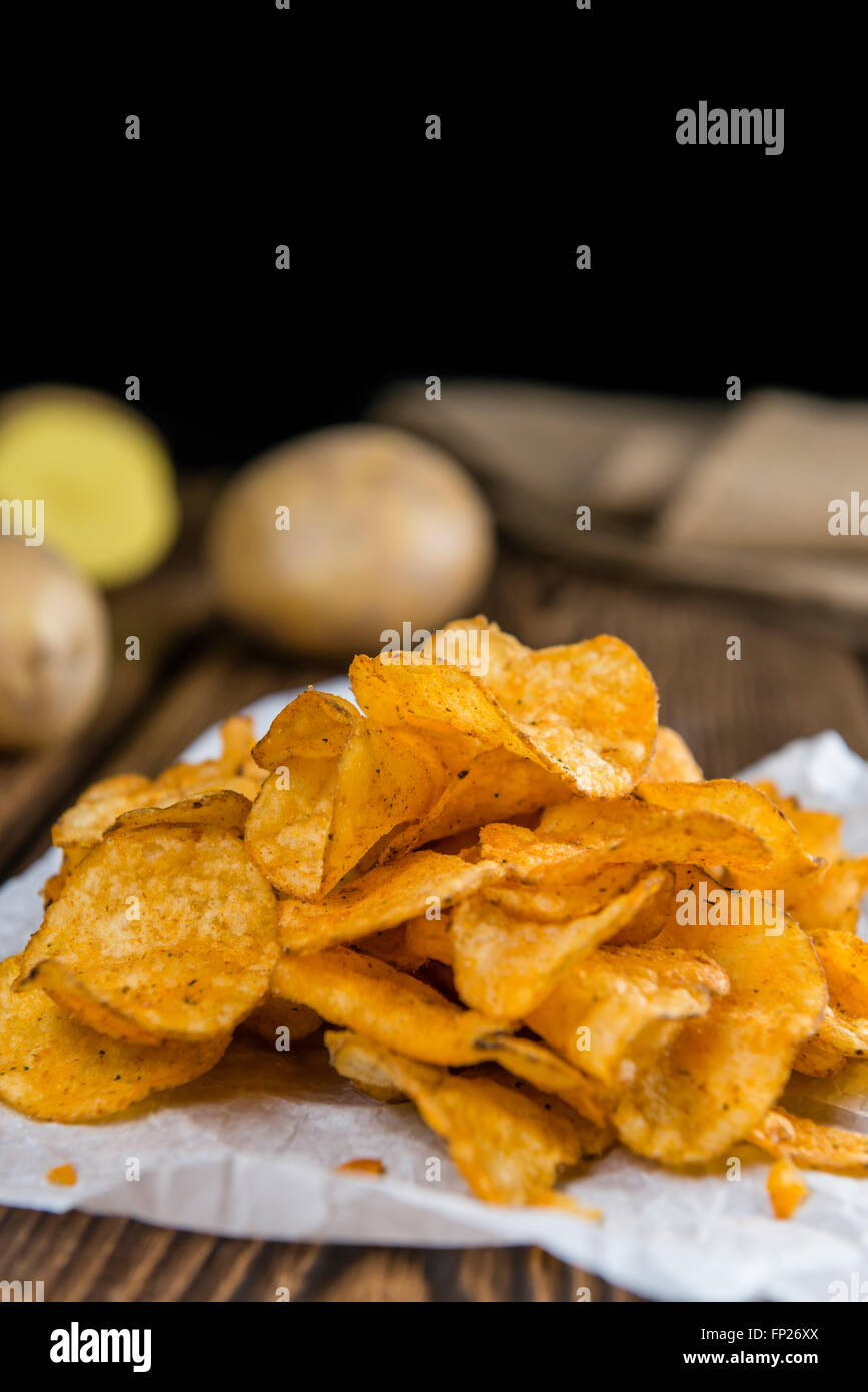 Portion of chilli Potato Chips (close-up shot) on wooden background ...