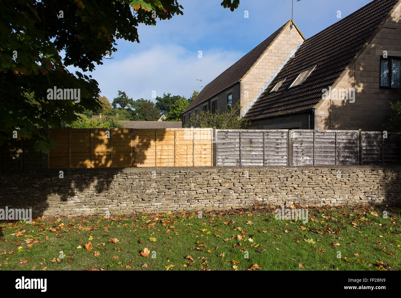 Residential fence with dry stone wall split between new and old wood ...