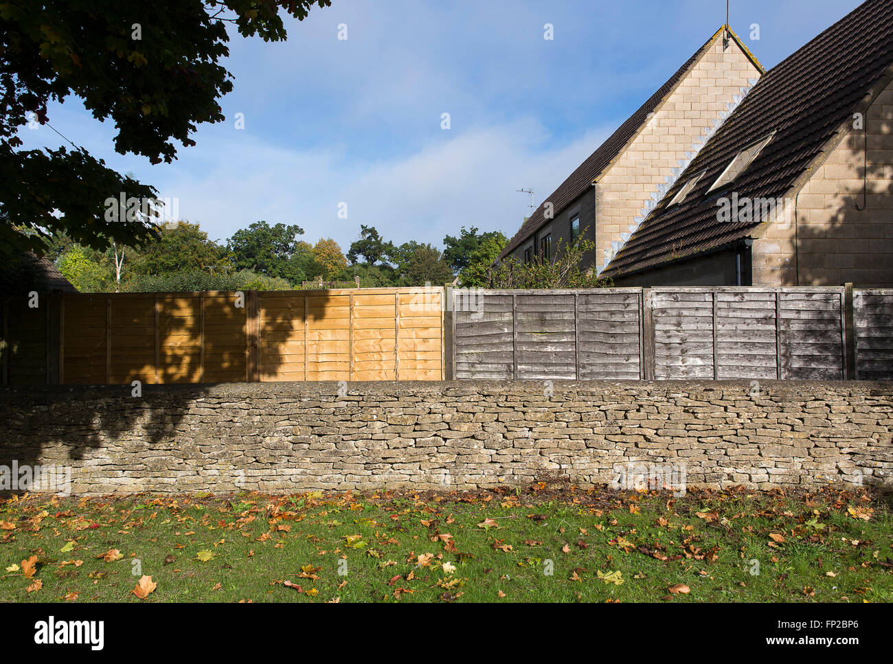 Residential fence with dry stone wall split between new and old wood ...